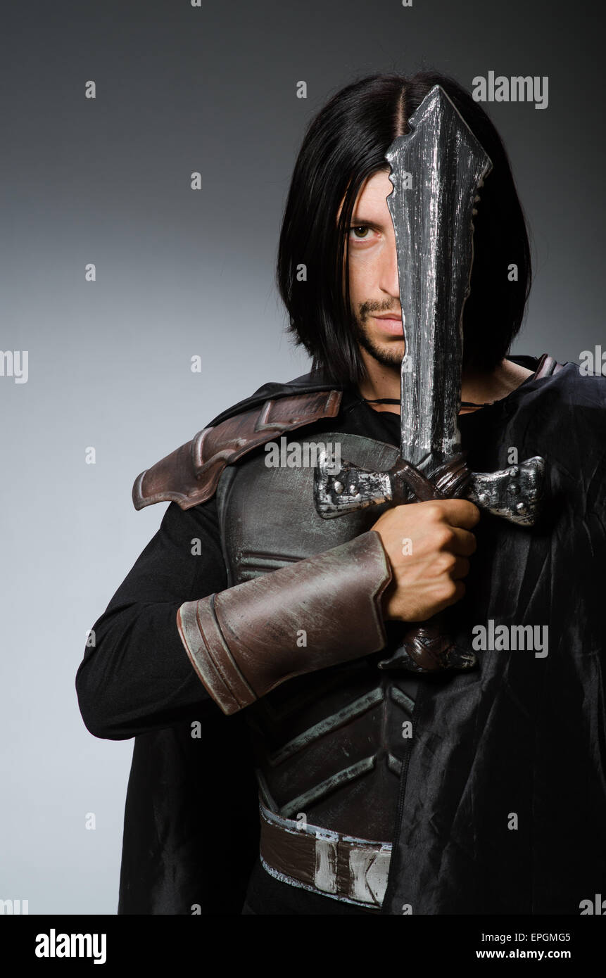 Angry knight with sword against dark background Stock Photo - Alamy
