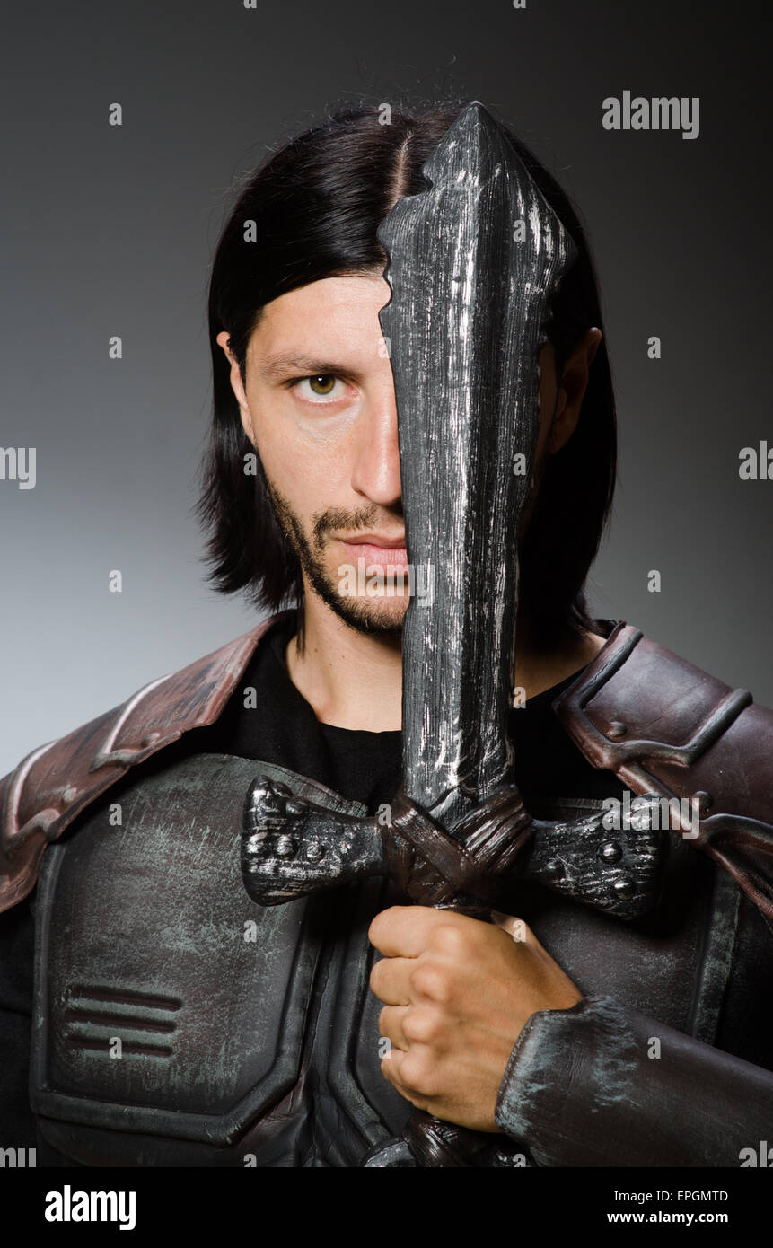 Angry knight with sword against dark background Stock Photo - Alamy