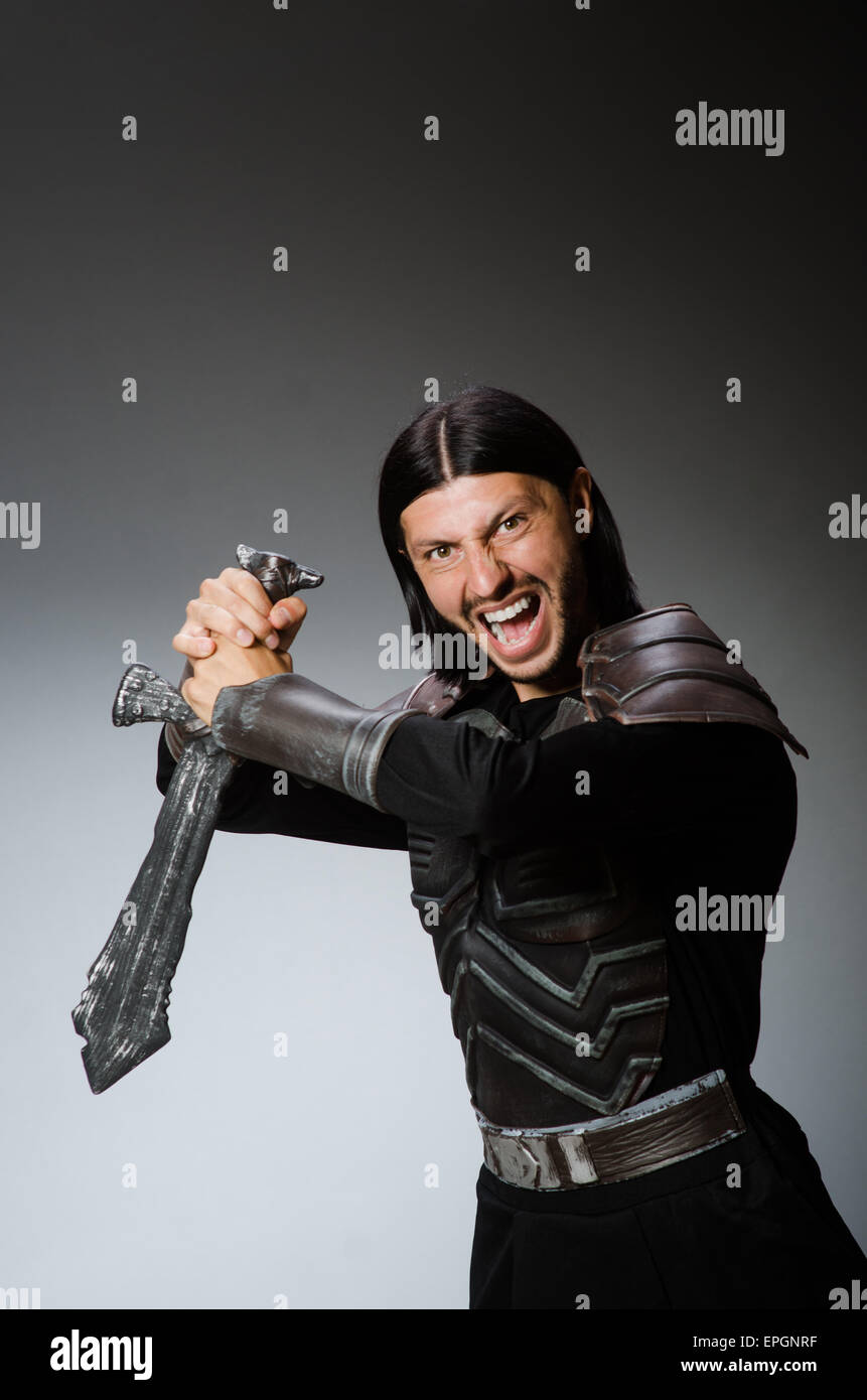Angry knight with sword against dark background Stock Photo - Alamy