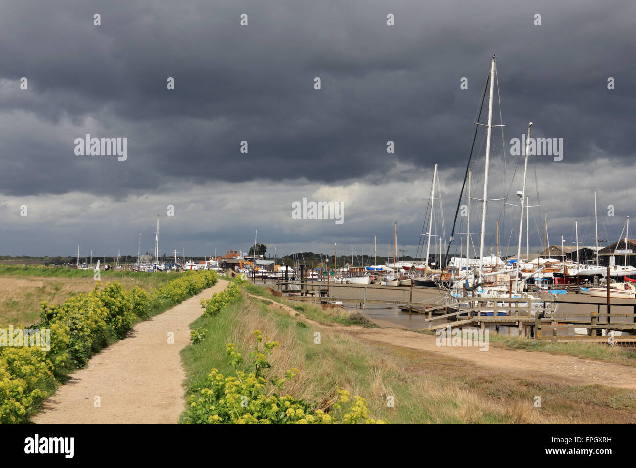 Stromy skies over the Suffolk coastal path beside the harbour at ...