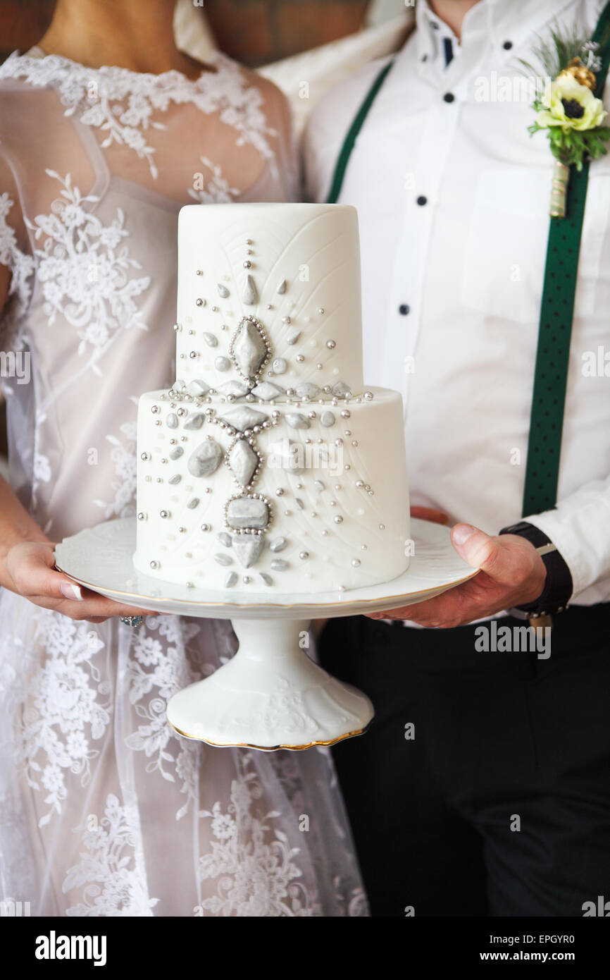 Cheerful married couple holding wedding cake Stock Photo - Alamy