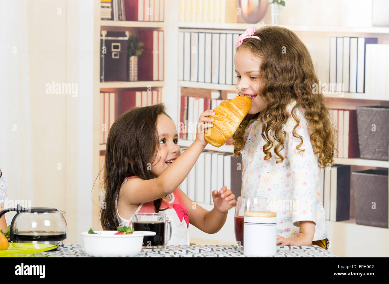 Cute little girl feeding bread to her sister Stock Photo - Alamy
