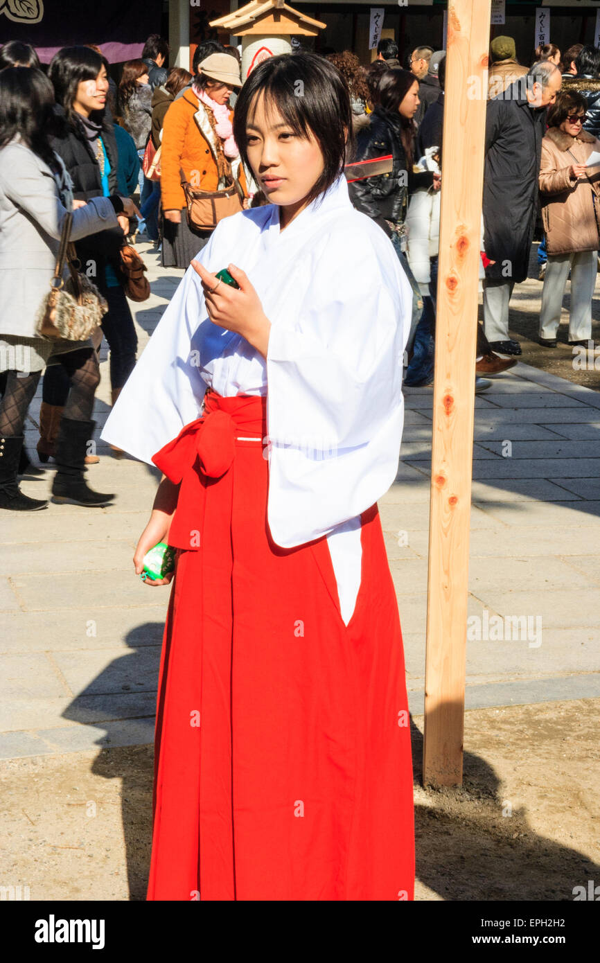 Japanese Shinto shrine at new year. A shrine Maiden, Miko, standing in ... Japanese Shinto shrine at new year. A shrine Maiden, Miko, standing in ...