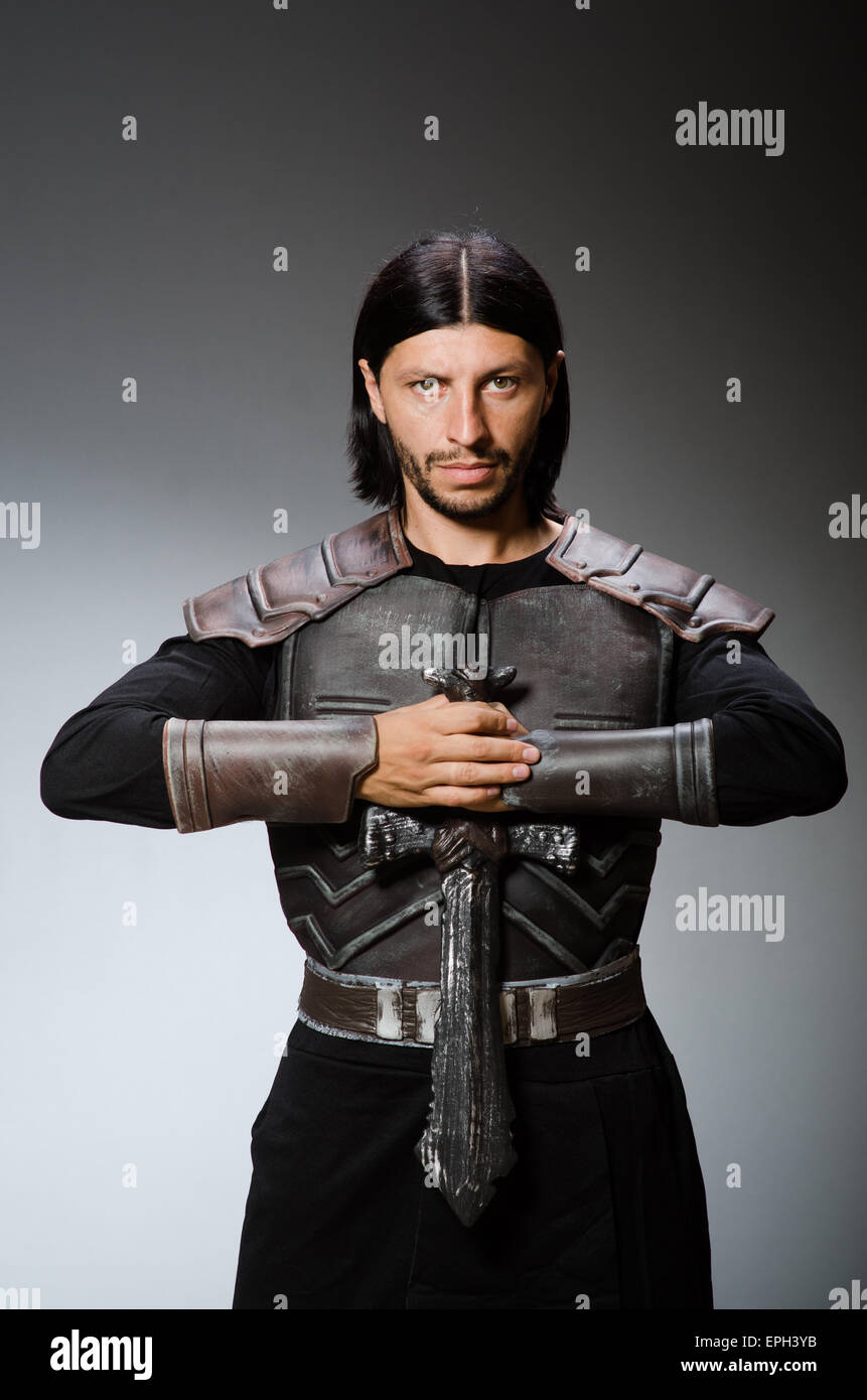 Angry knight with sword against dark background Stock Photo - Alamy