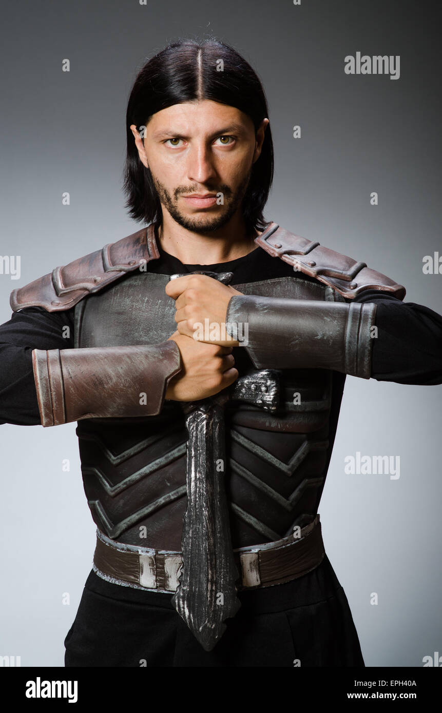 Angry knight with sword against dark background Stock Photo - Alamy