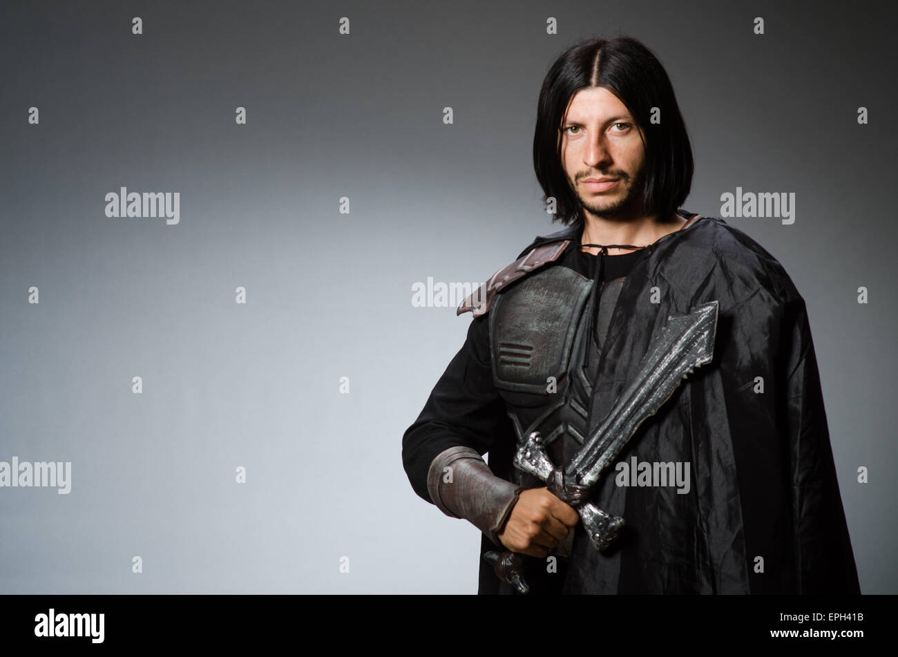 Angry knight with sword against dark background Stock Photo - Alamy