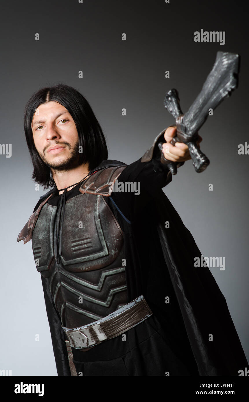 Angry knight with sword against dark background Stock Photo - Alamy