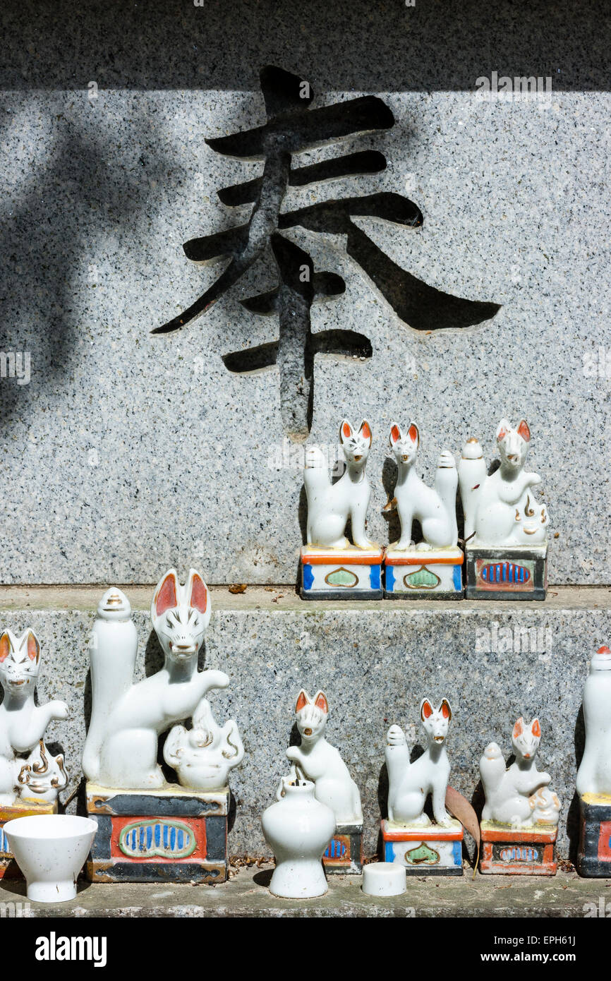 Small white and red porcelain fox statues, Inari, arranged under large ...