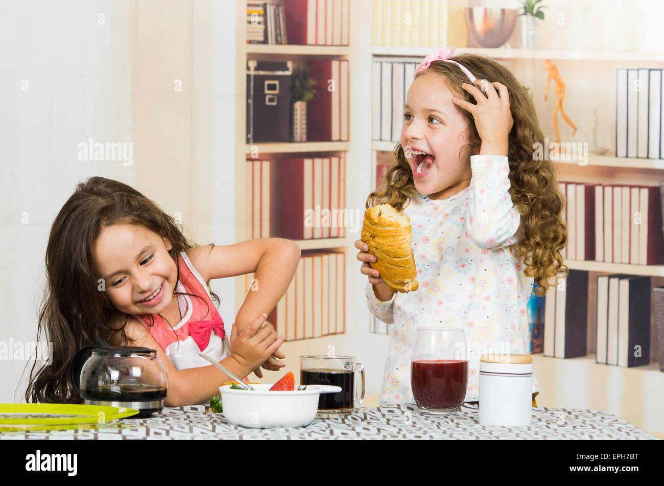 Two young preschooler girls eating at the table Stock Photo - Alamy