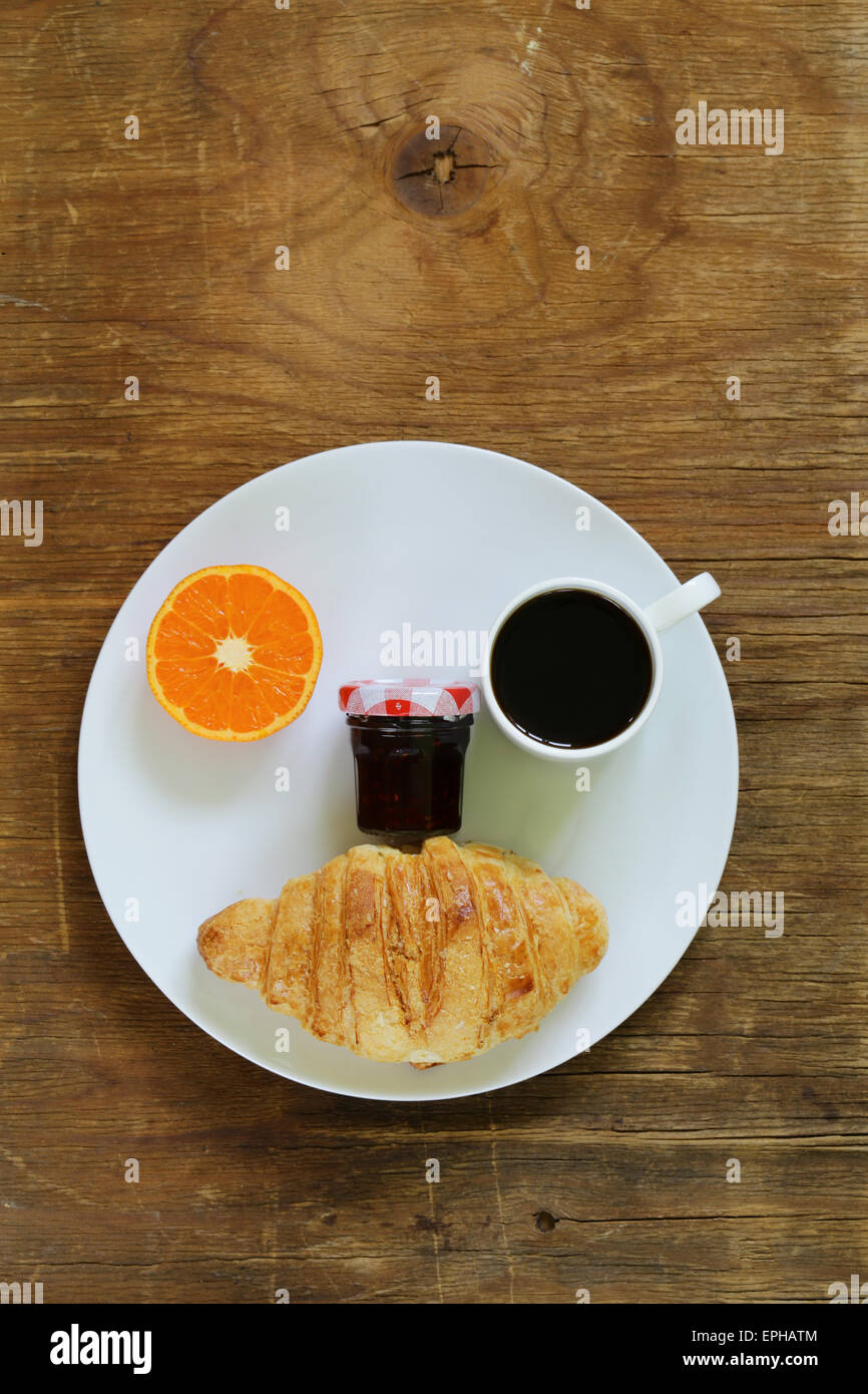 Breakfast serving funny face on the plate (jam, croissant, orange and ...