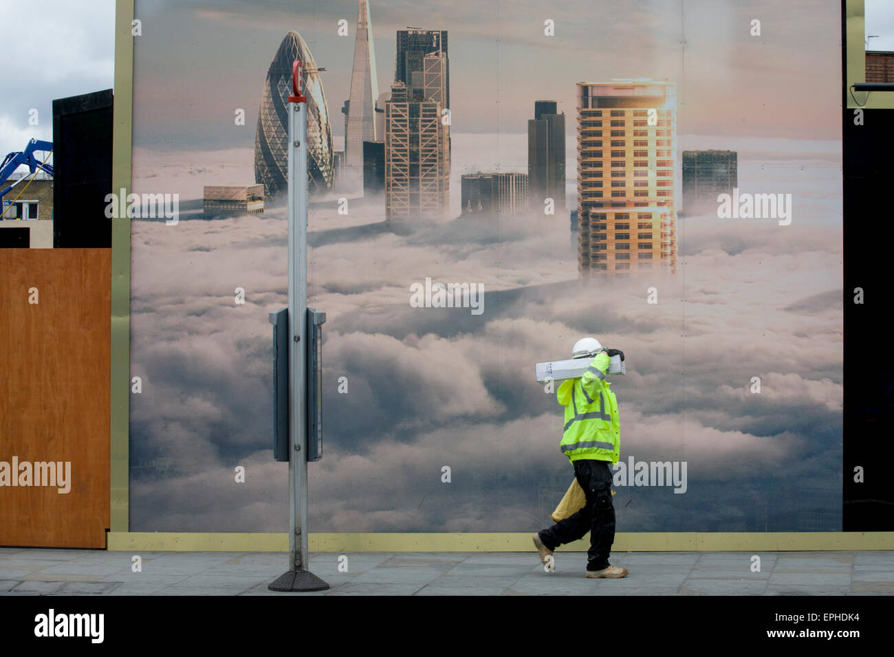 Construction workman walks beneath a property developer's billboard ...