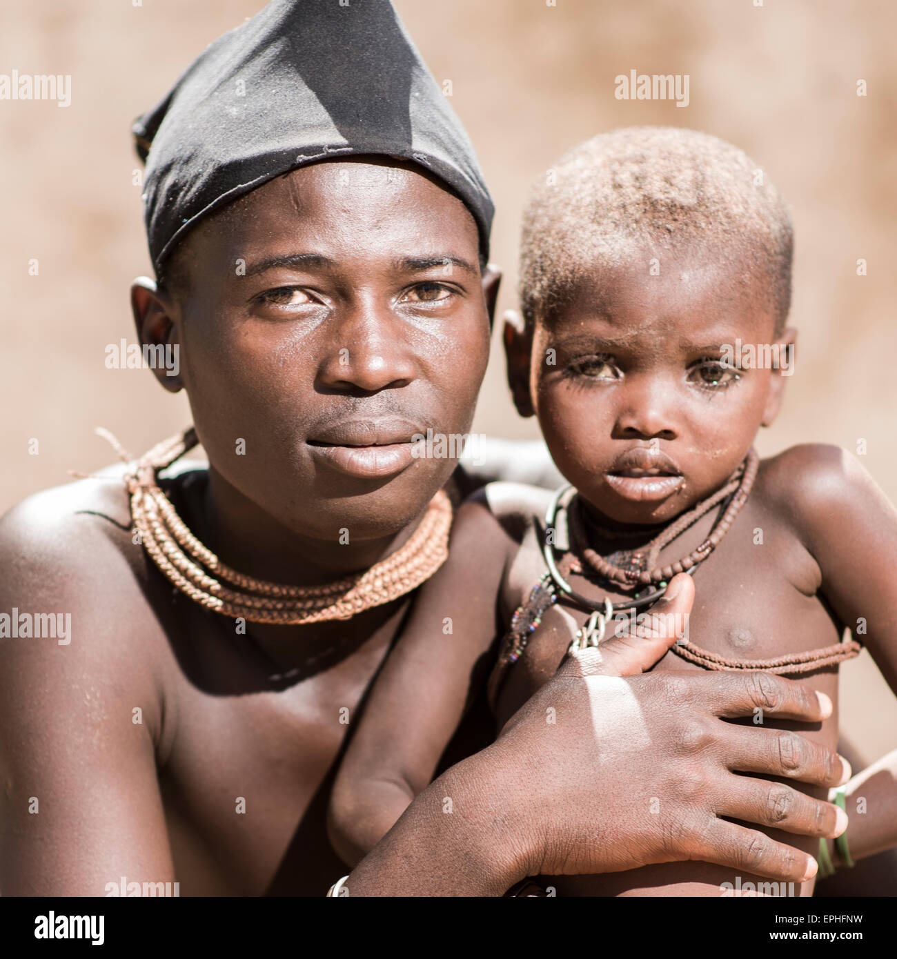 Africa, Namibia. Himba Tribe Village. Close up of man holding child ...