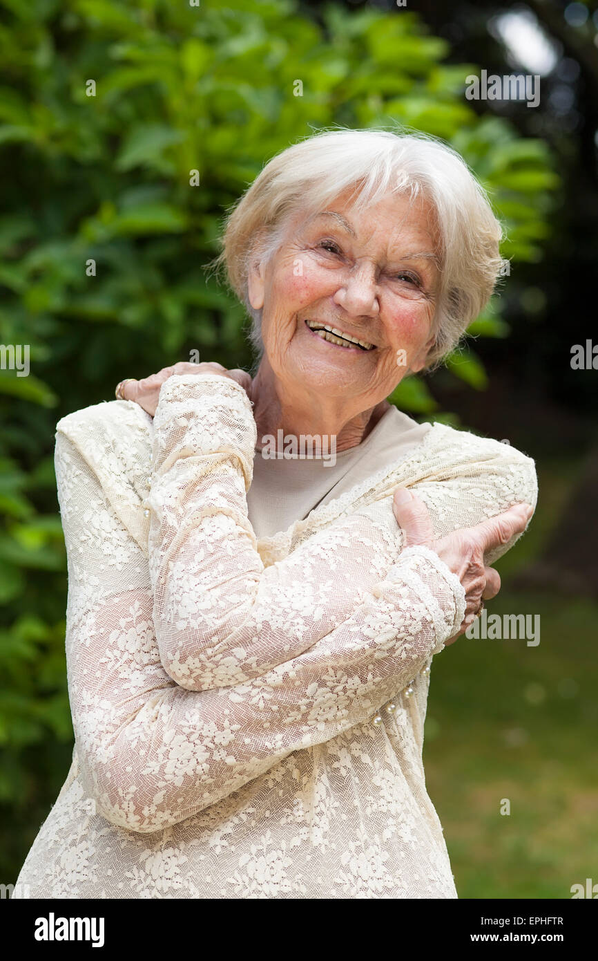 Happy laughing elderly woman in a pretty lacy top standing hugging ...
