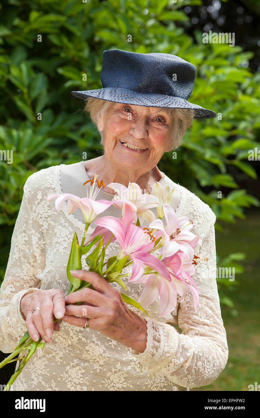 Elderly lady in stylish vintage clothing standing in her lush green ...