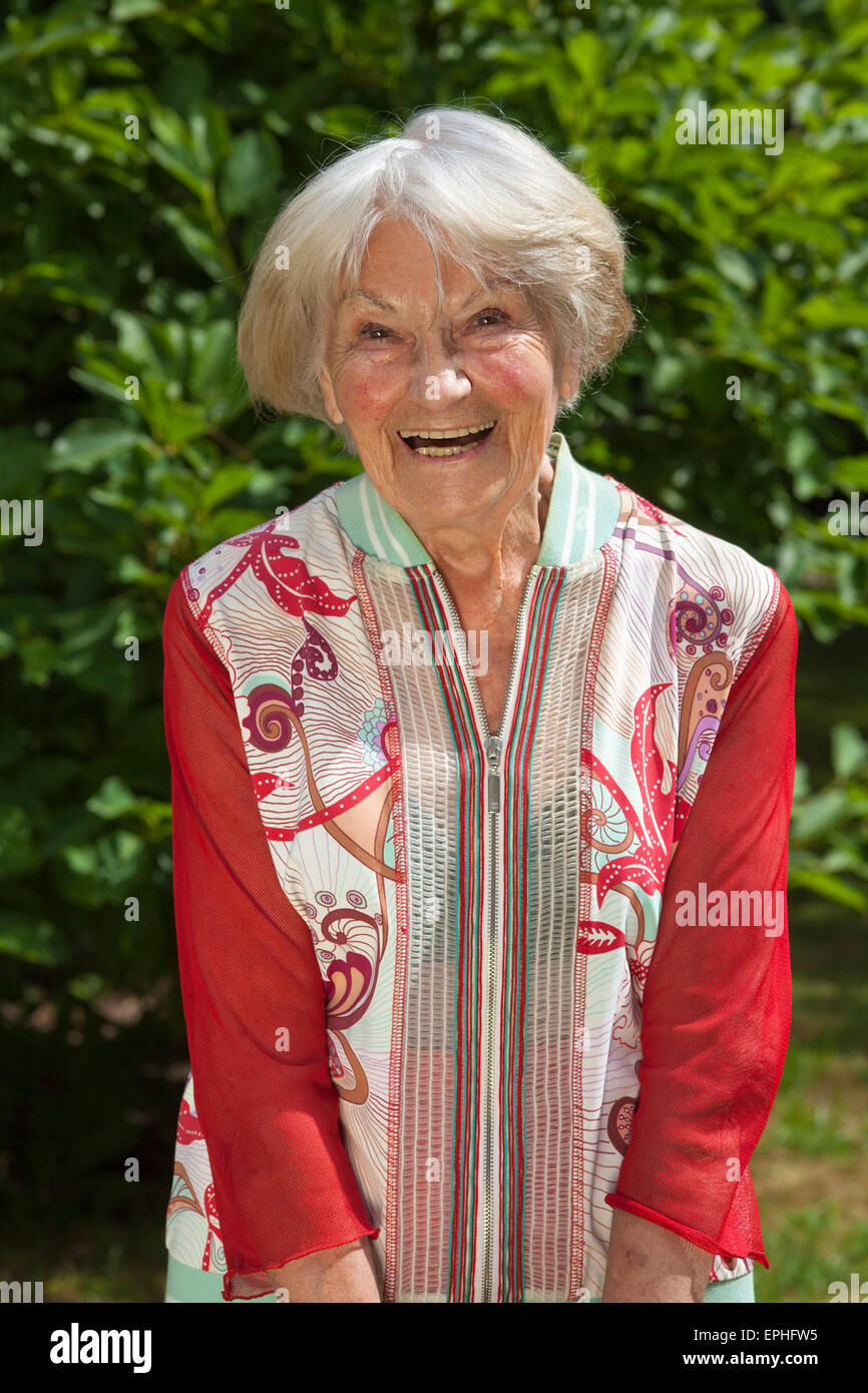 Laughing attractive female pensioner in a stylish red outfit smiling ...