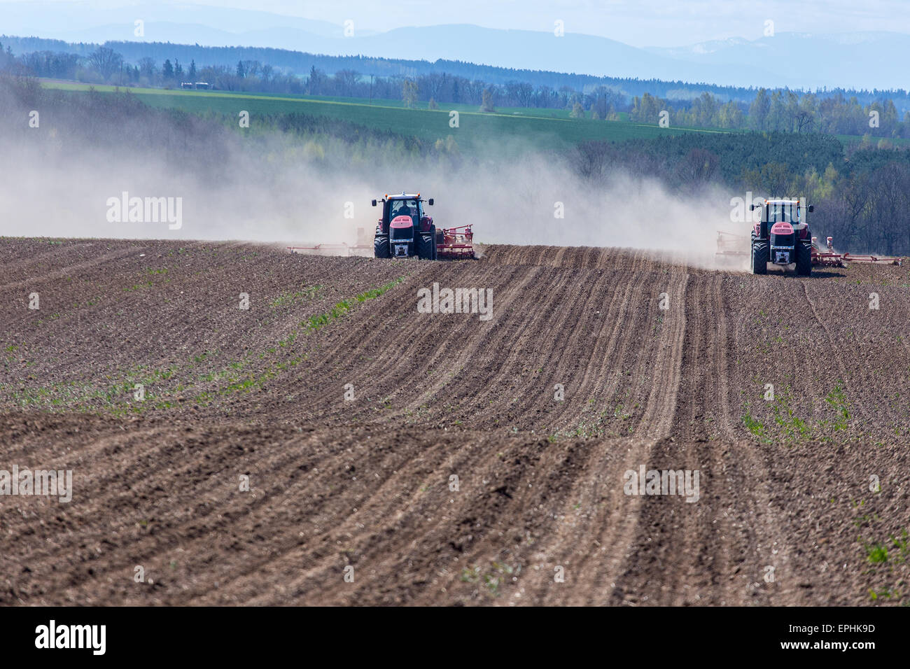 The tractor harrowing the large brown field in spring season Stock ...