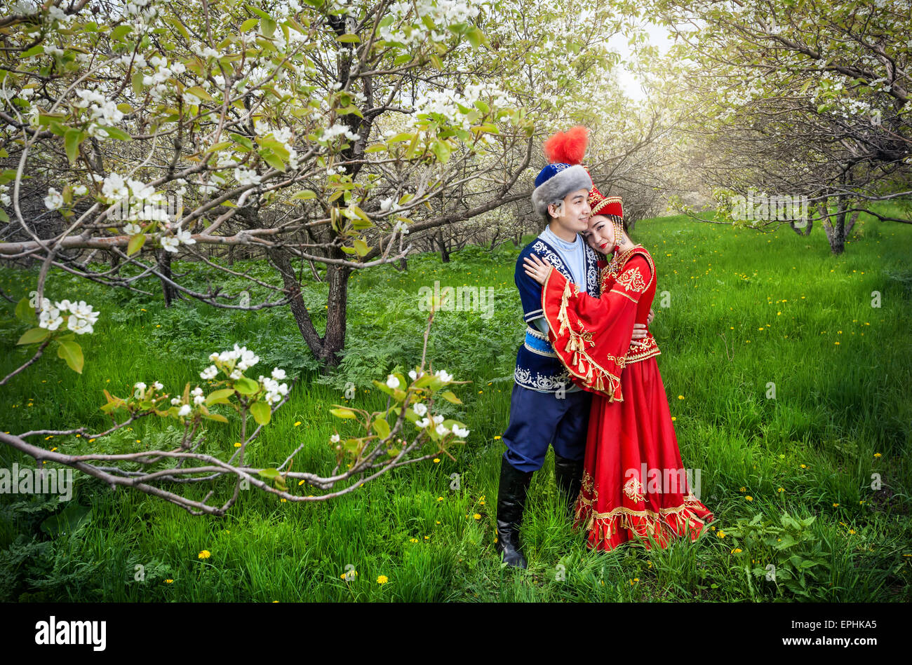 Couple in Kazakh costume in Spring Blooming apple garden of Almaty ...