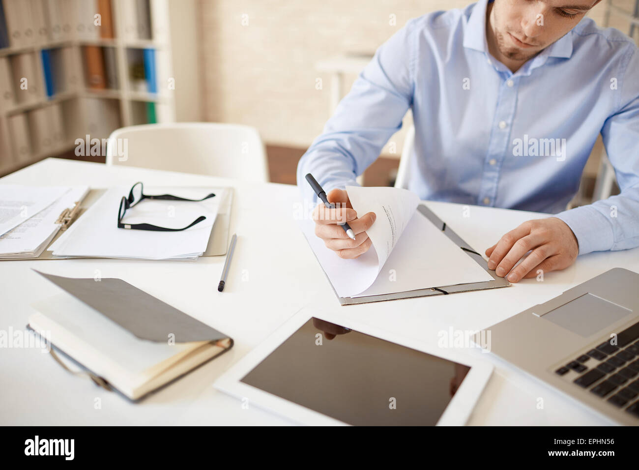 Young employee reading papers at workplace Stock Photo - Alamy