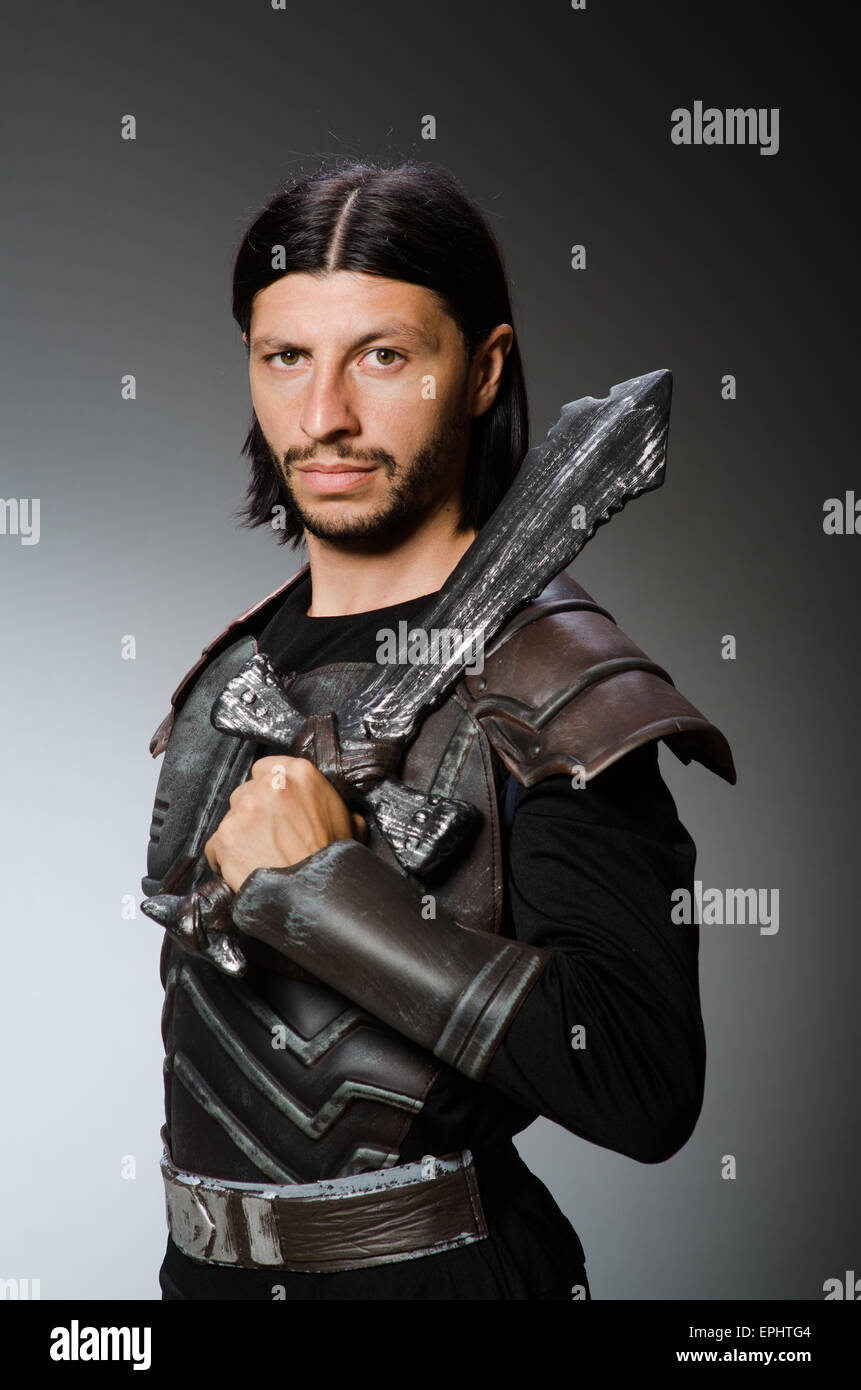 Angry knight with sword against dark background Stock Photo - Alamy