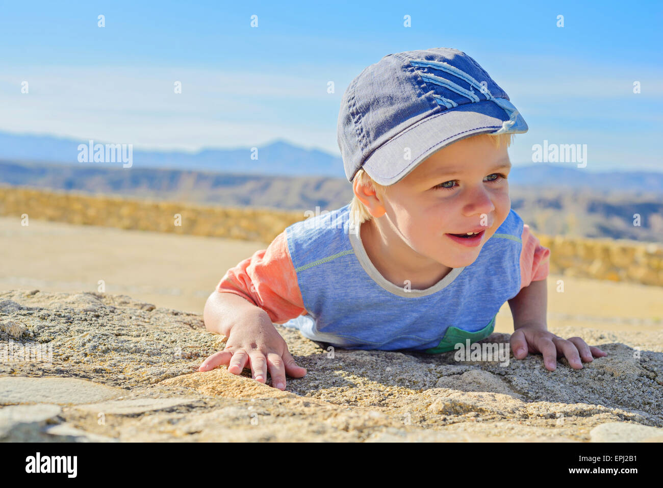 Smiling little boy laying down on the rock Stock Photo - Alamy