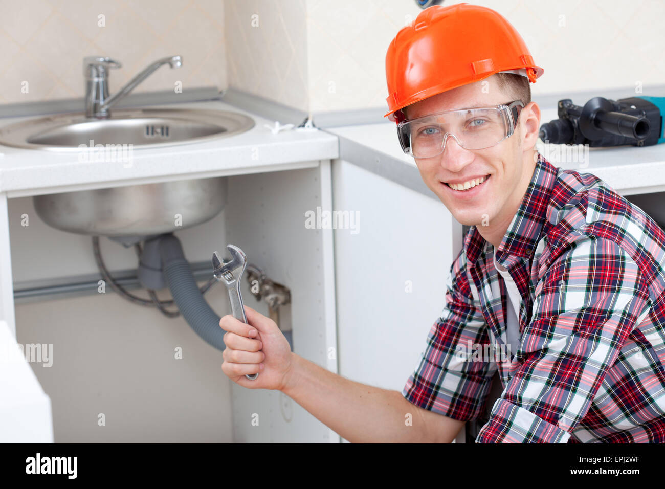 smiling plumber near the kitchen sink Stock Photo - Alamy