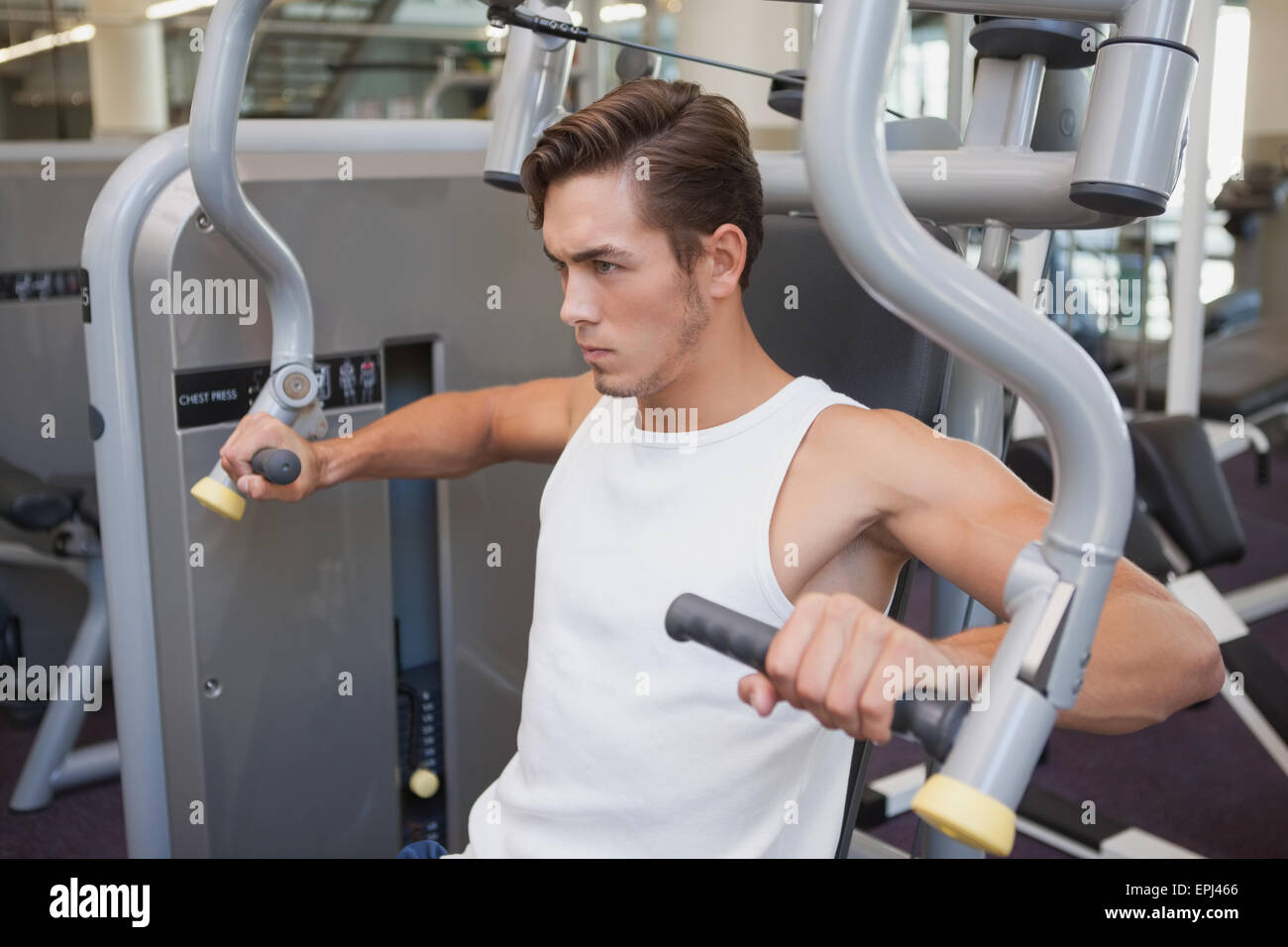 Fit man using weights machine for arms Stock Photo - Alamy