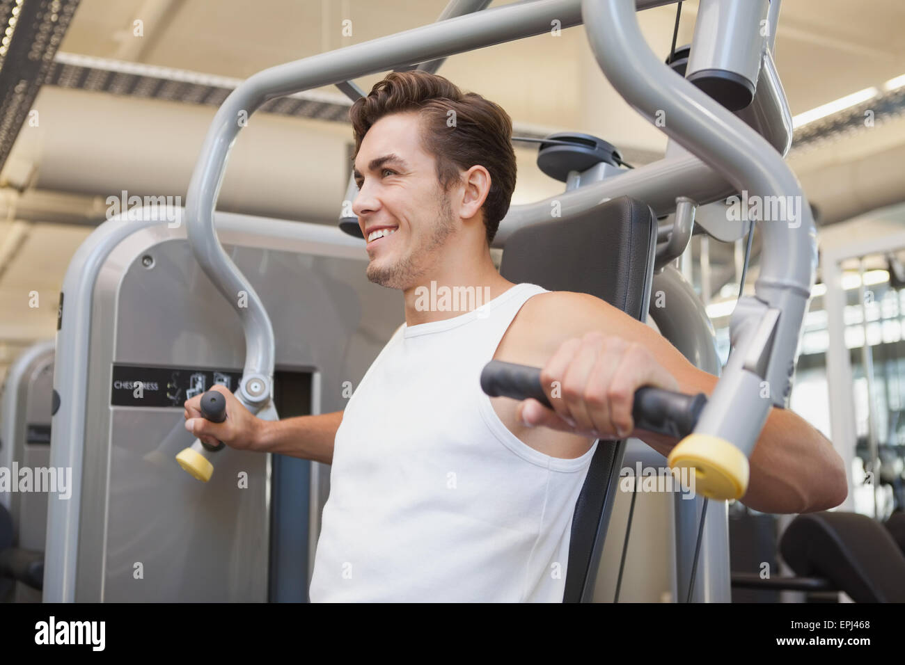Fit man using weights machine for arms Stock Photo - Alamy