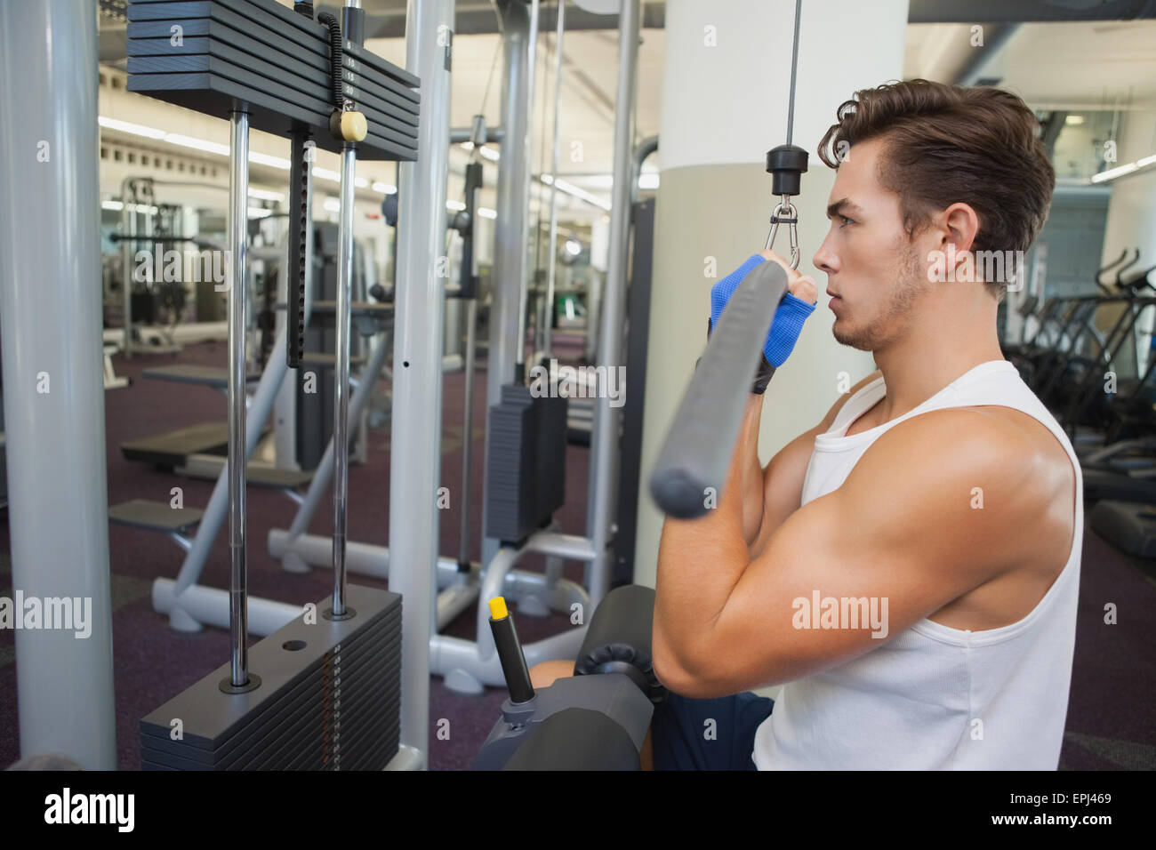 Fit man using weights machine for arms Stock Photo - Alamy