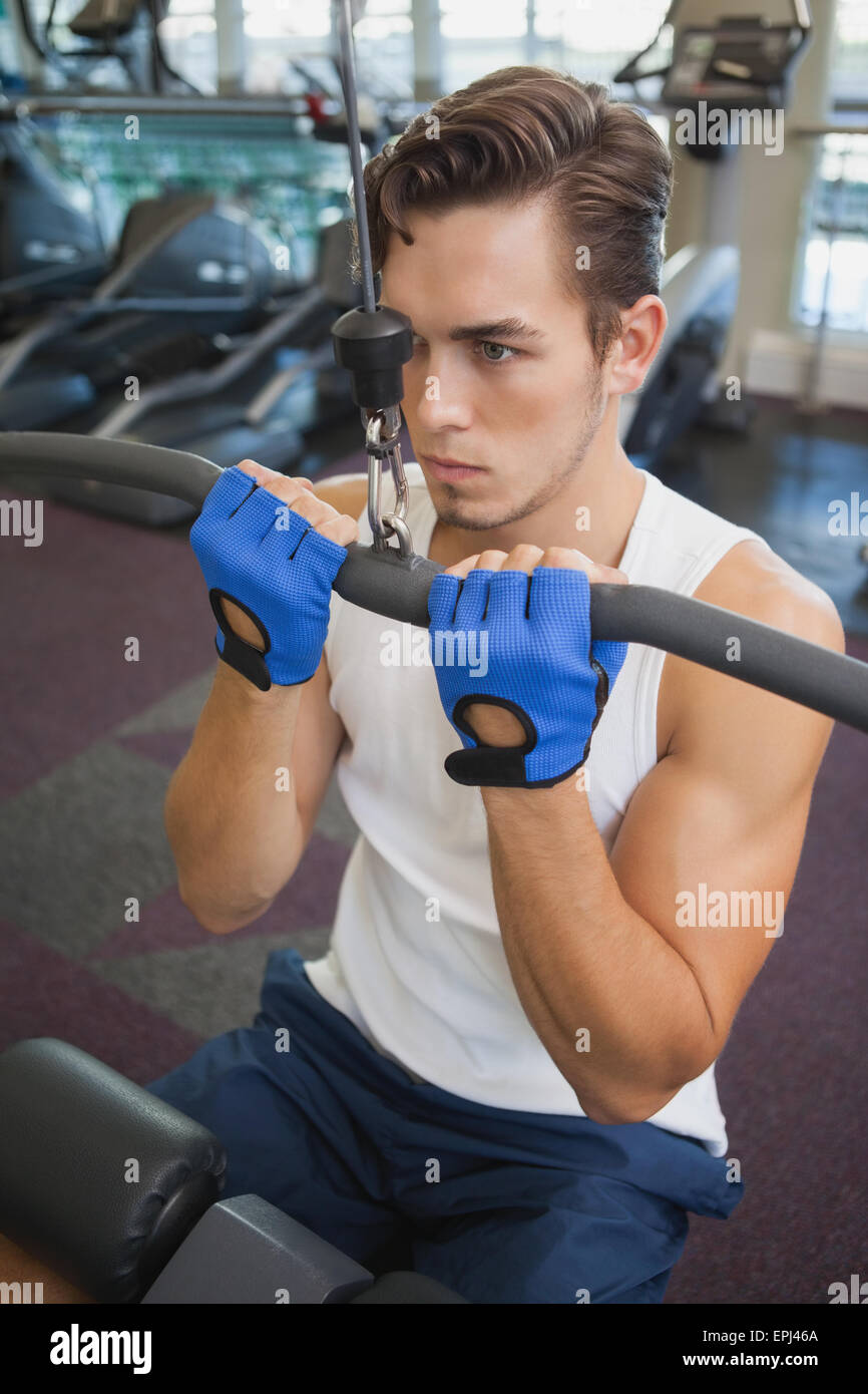 Fit man using weights machine for arms Stock Photo - Alamy