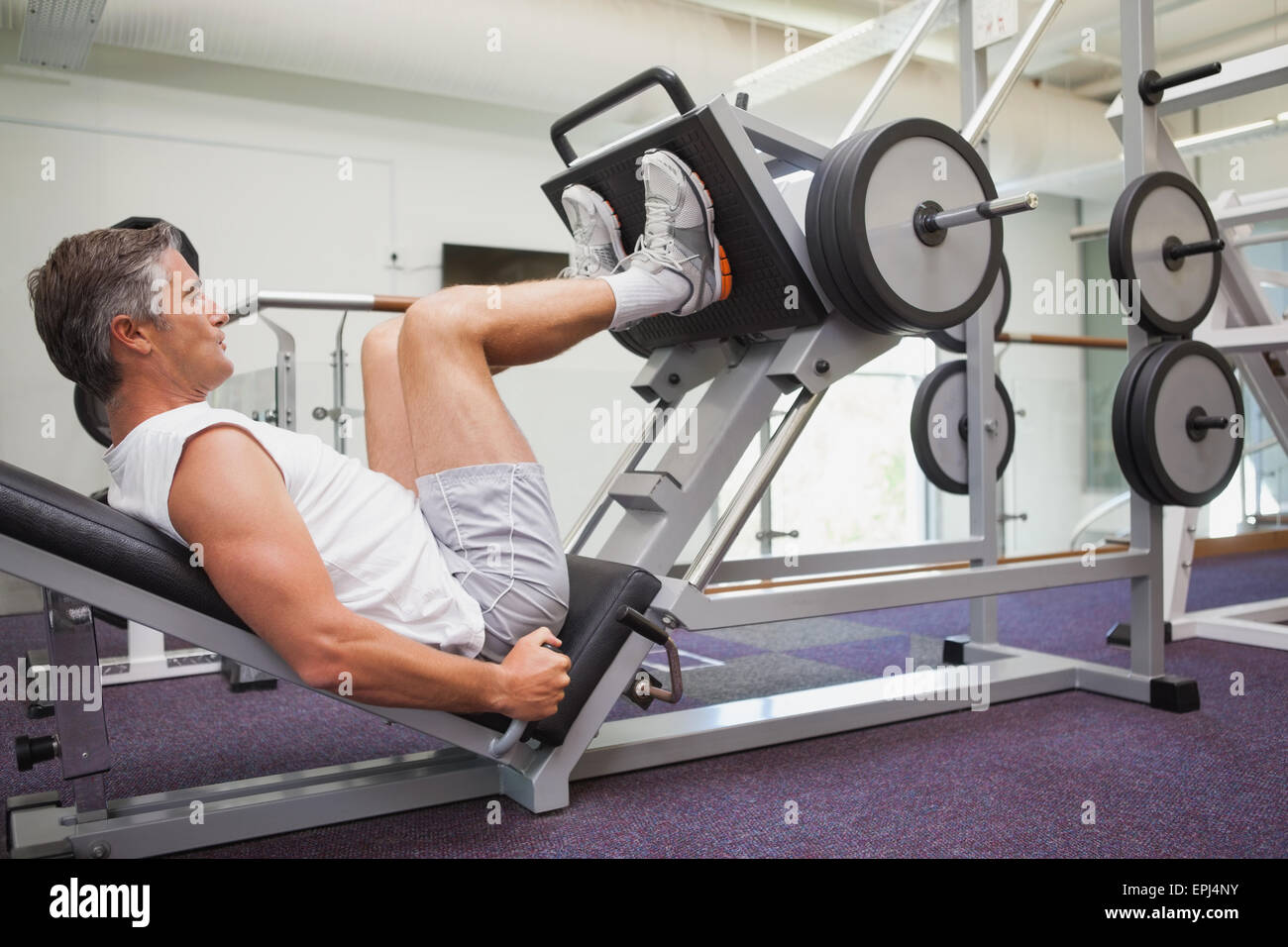 Fit man using weights machine for legs Stock Photo - Alamy