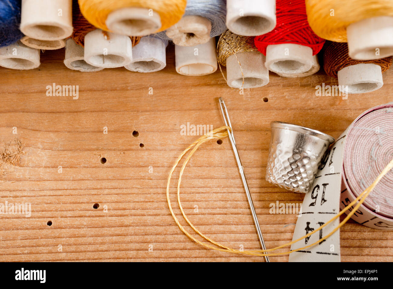 needle with thread and thimble on the wooden desk Stock Photo - Alamy