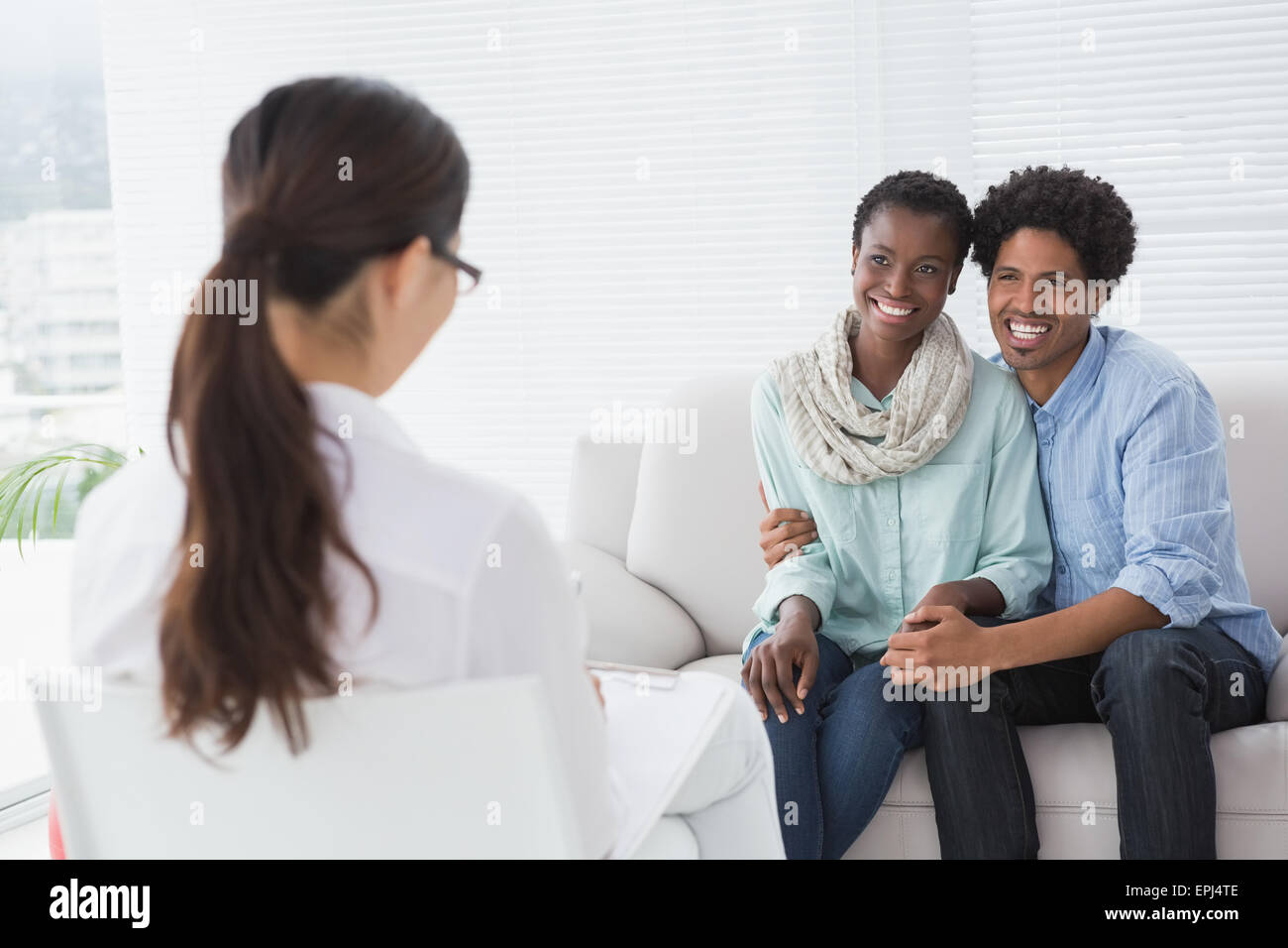 Reconciled couple smiling at their therapist Stock Photo - Alamy