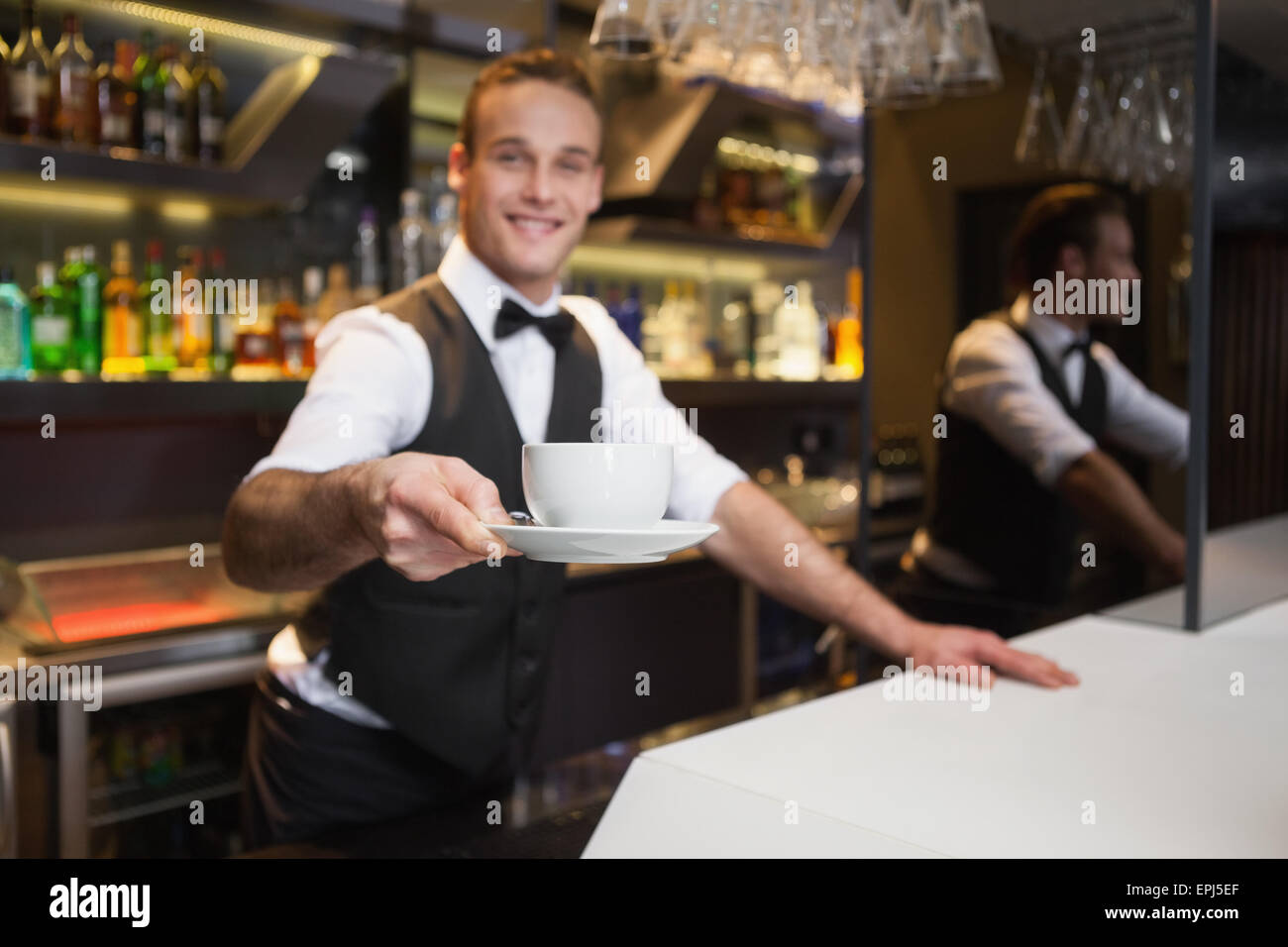 Smiling waiter offering cup of coffee smiling at camera Stock Photo - Alamy