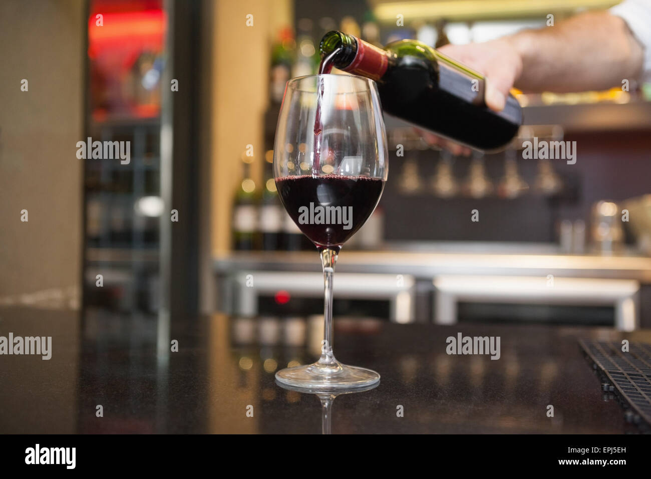 Hand pouring red wine into glass Stock Photo - Alamy