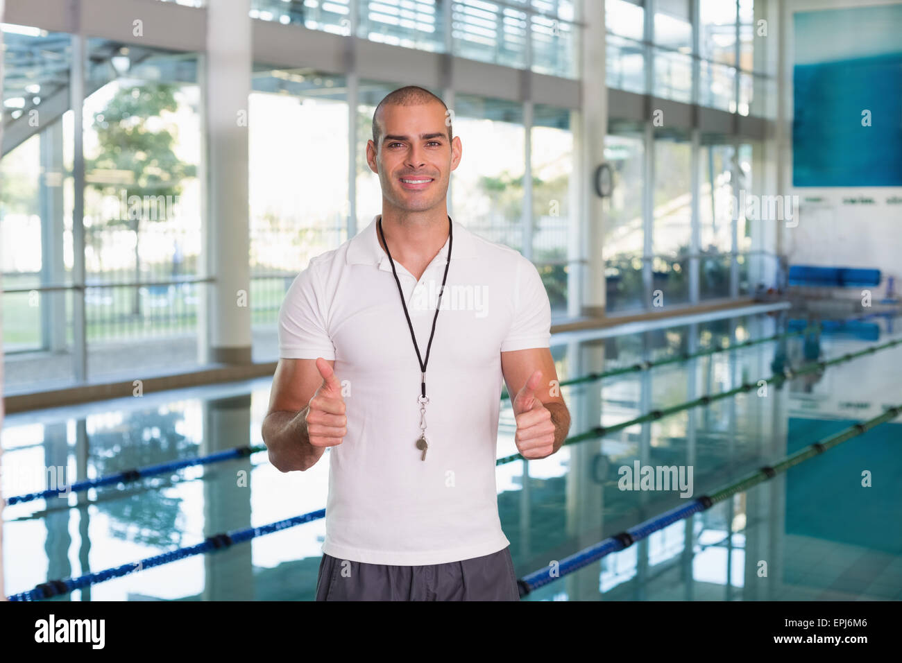 Swimming coach gesturing thumbs up by pool at leisure center Stock ...