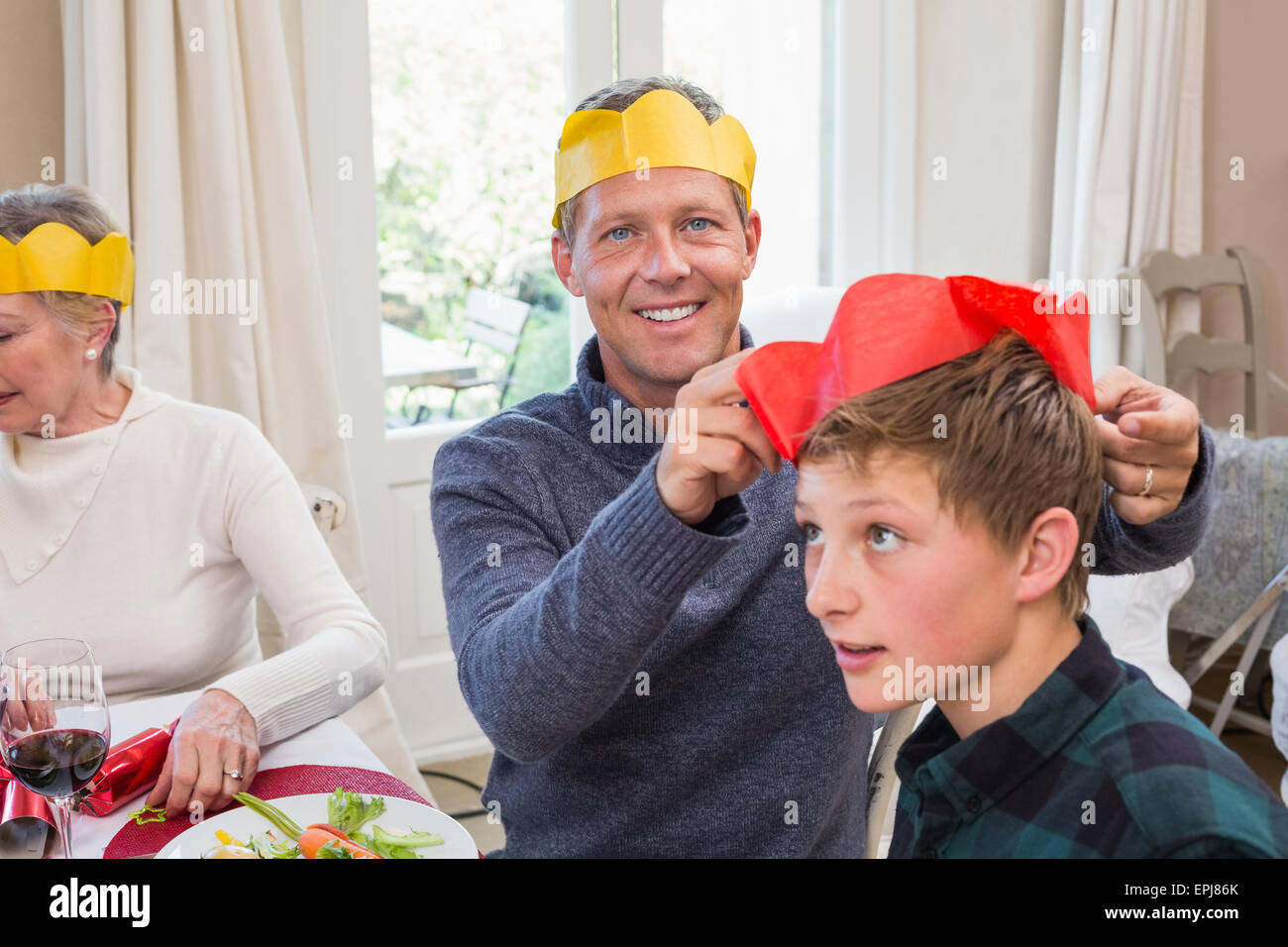 Smiling father putting party hat on sons head Stock Photo - Alamy