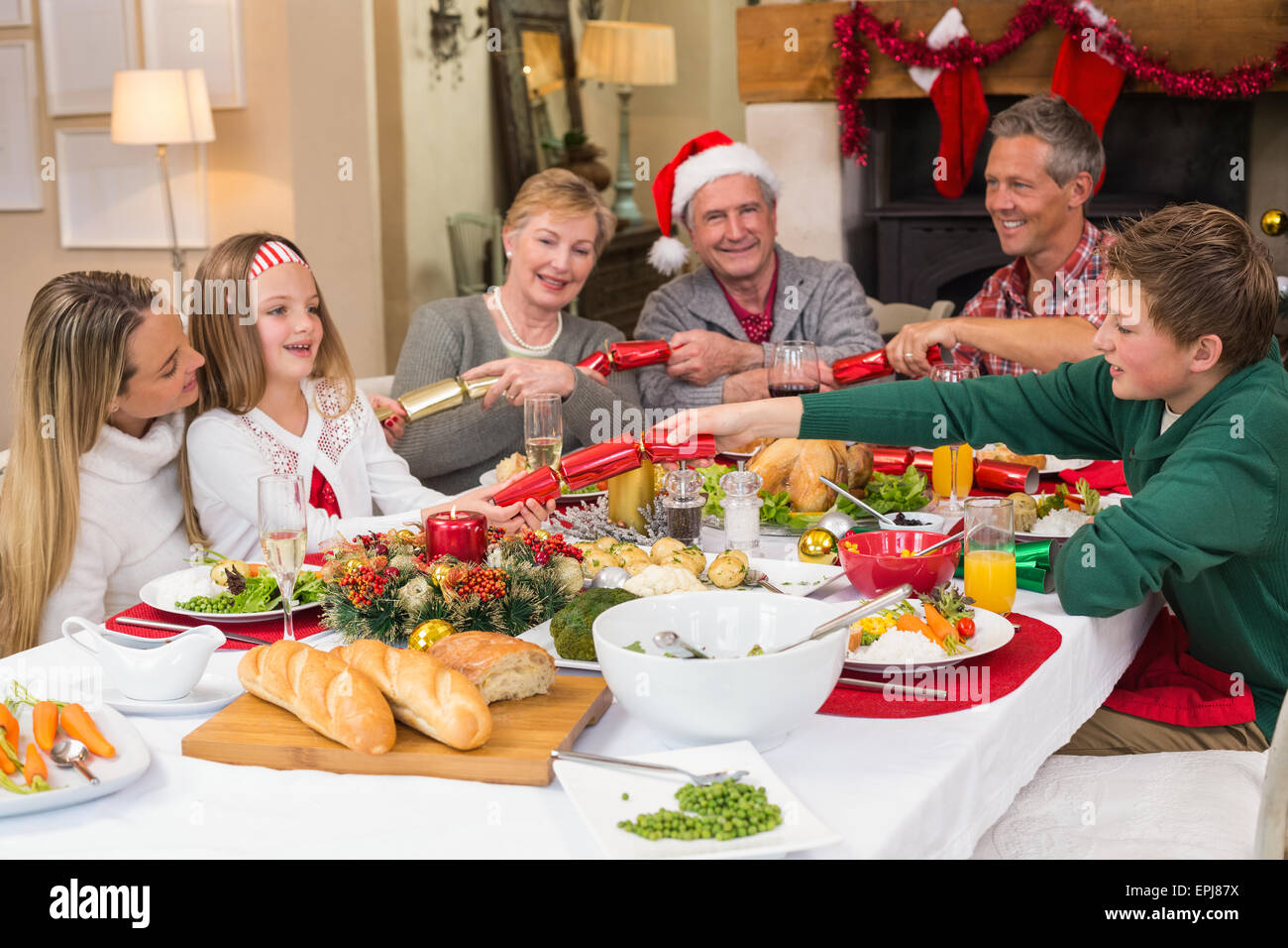 Smiling family pulling christmas crackers at the dinner table Stock ...