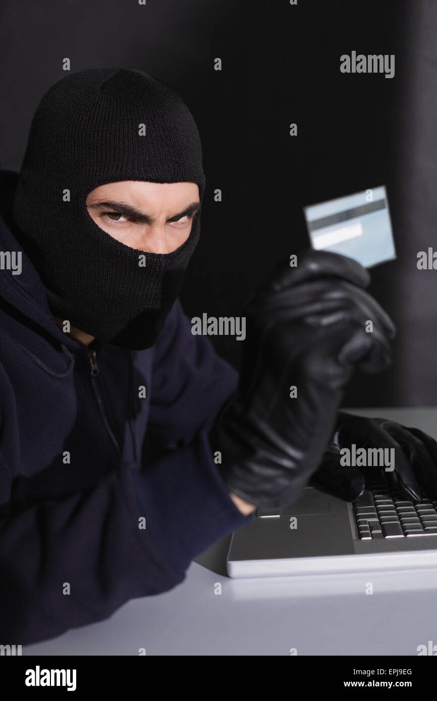 Angry hacker using credit card and laptop Stock Photo - Alamy