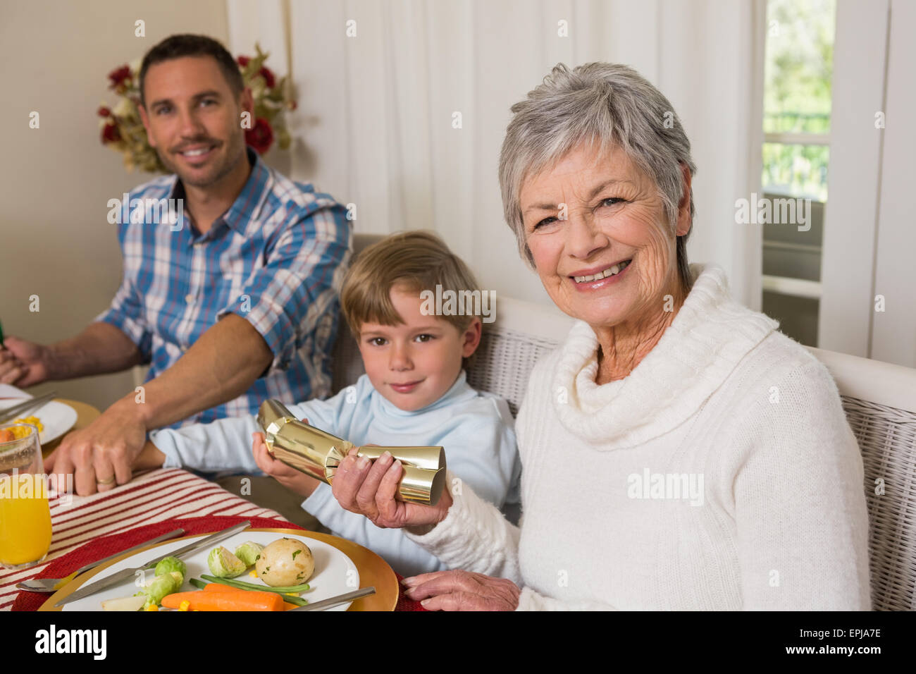Smiling family pulling christmas crackers at the dinner table Stock ...