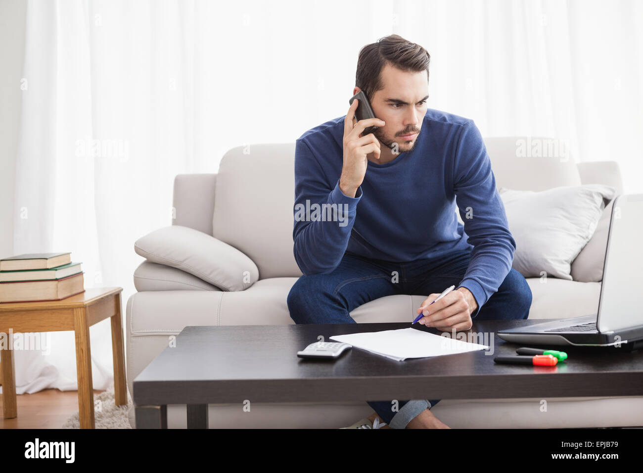 Young man paying his bills with laptop Stock Photo - Alamy