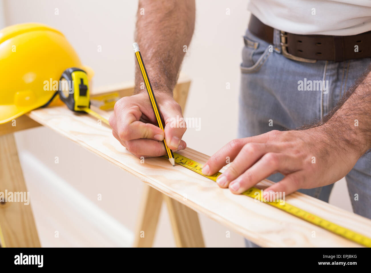 Casual man measuring plank of wood Stock Photo - Alamy