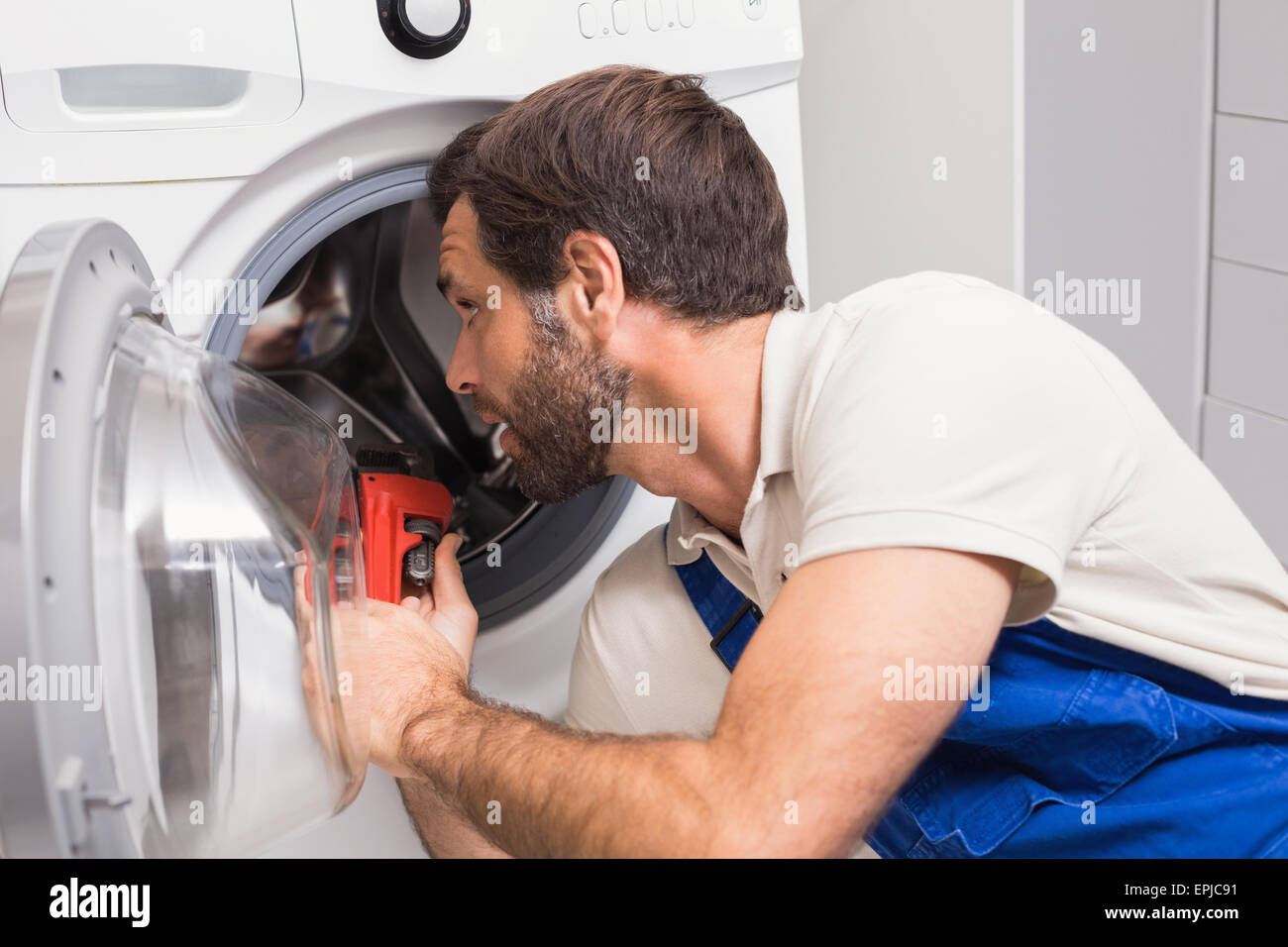 Handyman fixing a washing machine Stock Photo - Alamy