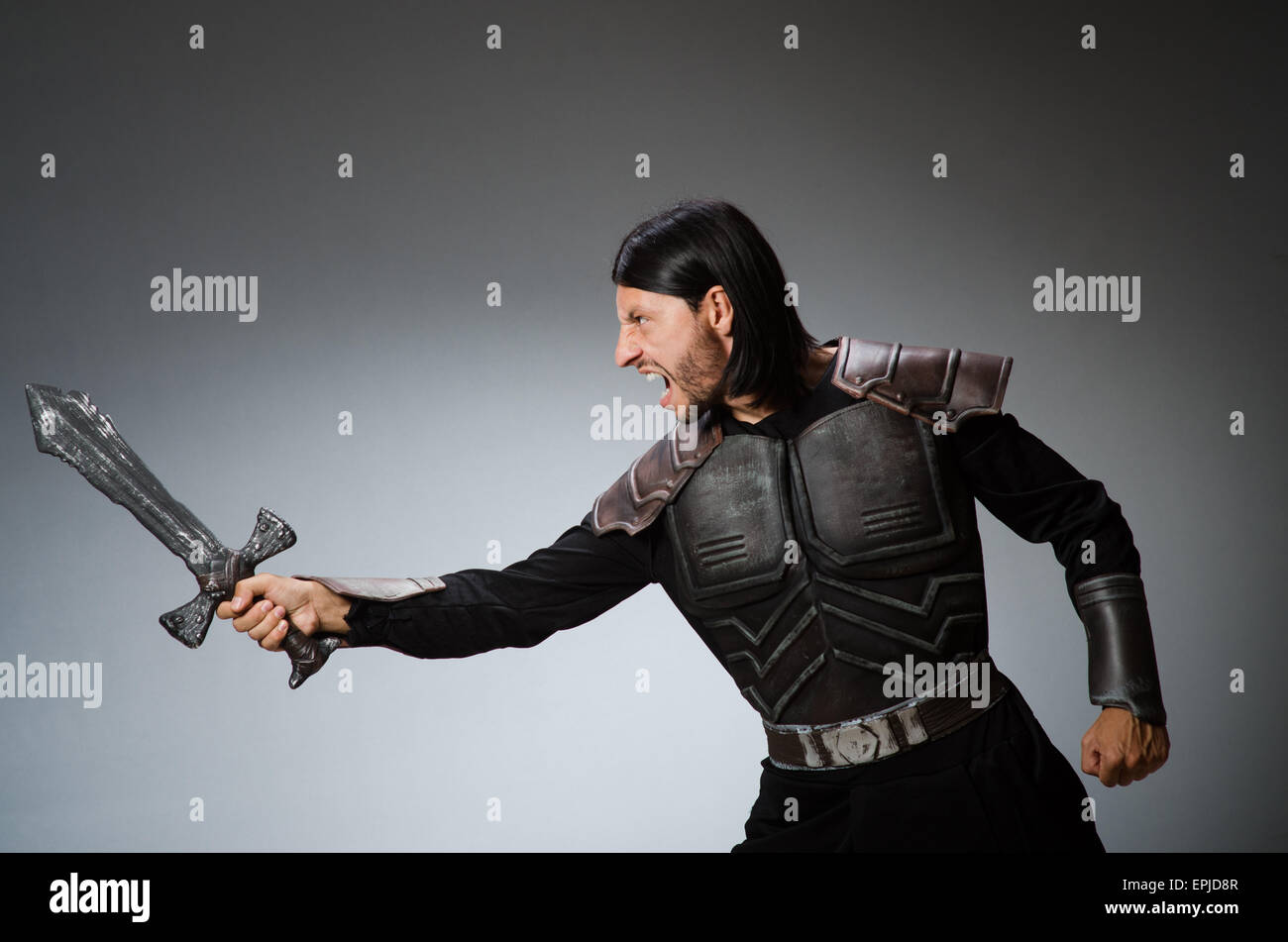 Angry knight with sword against dark background Stock Photo - Alamy