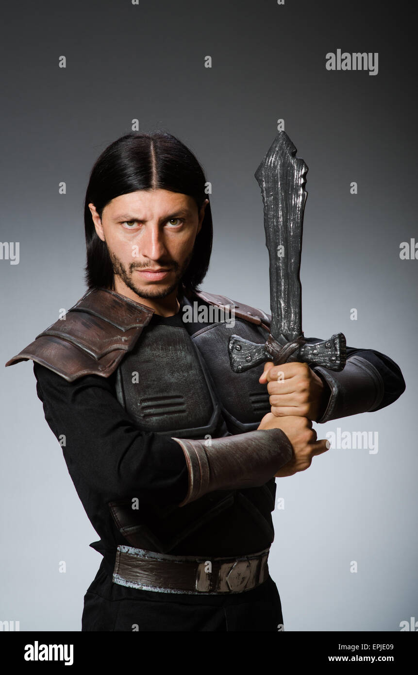 Angry knight with sword against dark background Stock Photo - Alamy