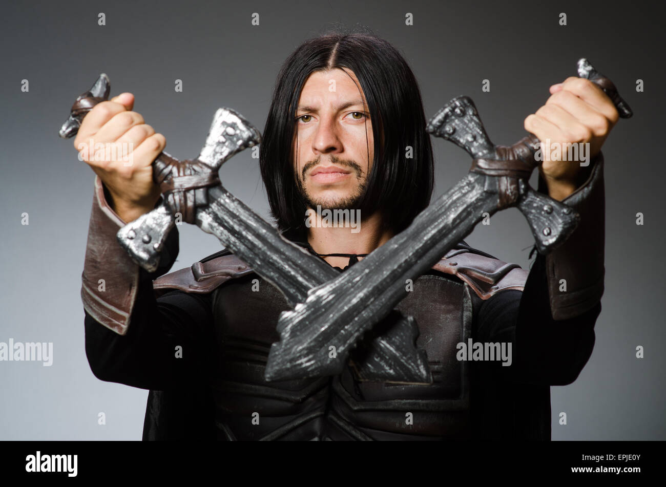 Angry knight with sword against dark background Stock Photo - Alamy