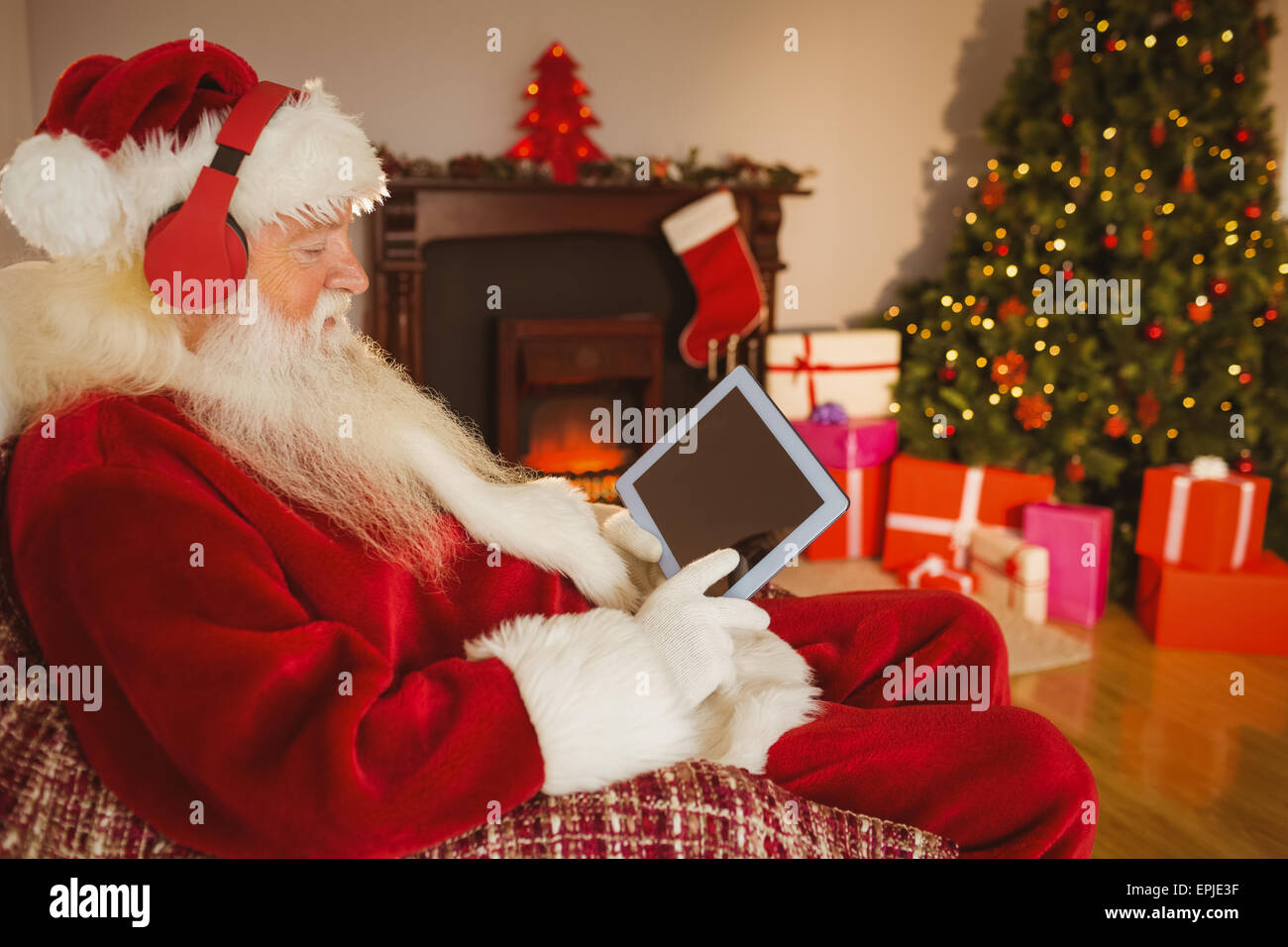 Santa listening music and touching tablet Stock Photo - Alamy
