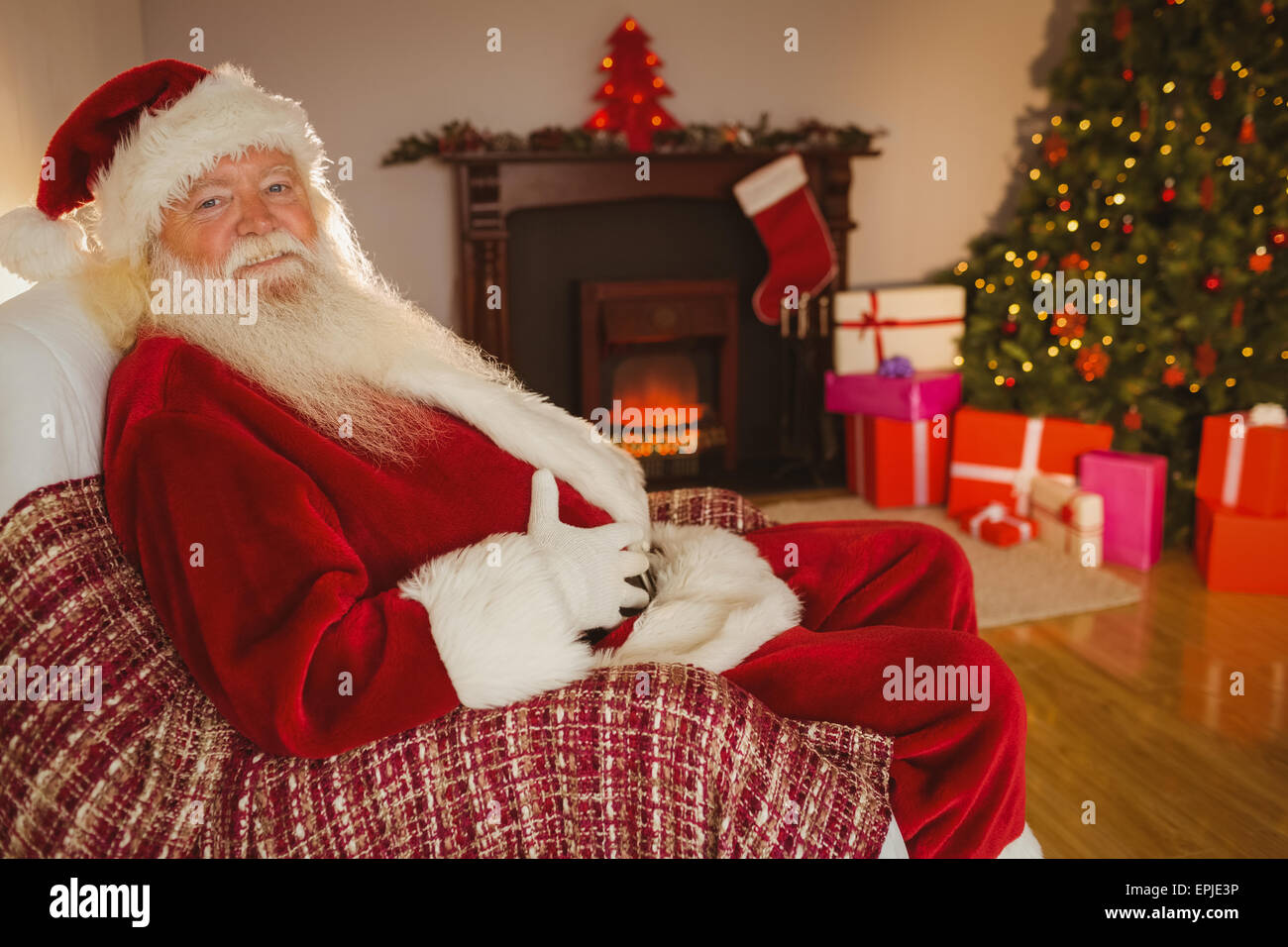 Smiling santa sitting and holding his belly Stock Photo - Alamy