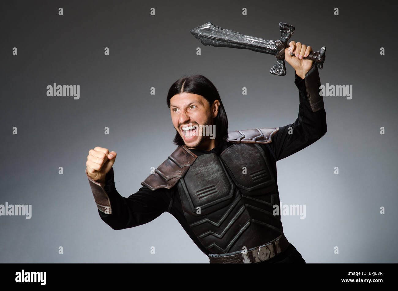 Angry knight with sword against dark background Stock Photo - Alamy