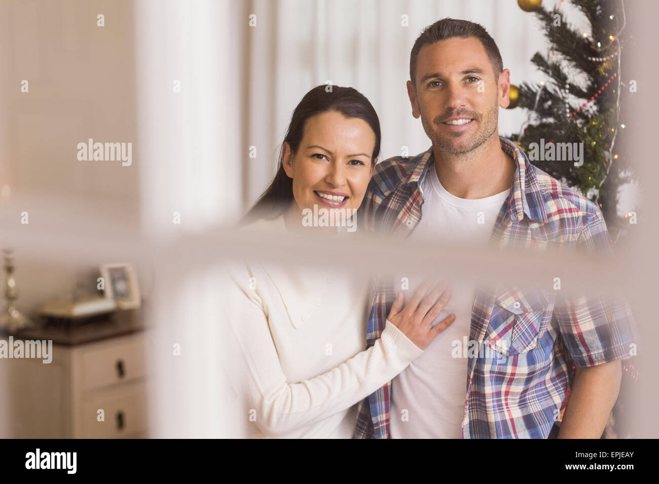 Smiling couple cuddling near the christmas tree Stock Photo - Alamy
