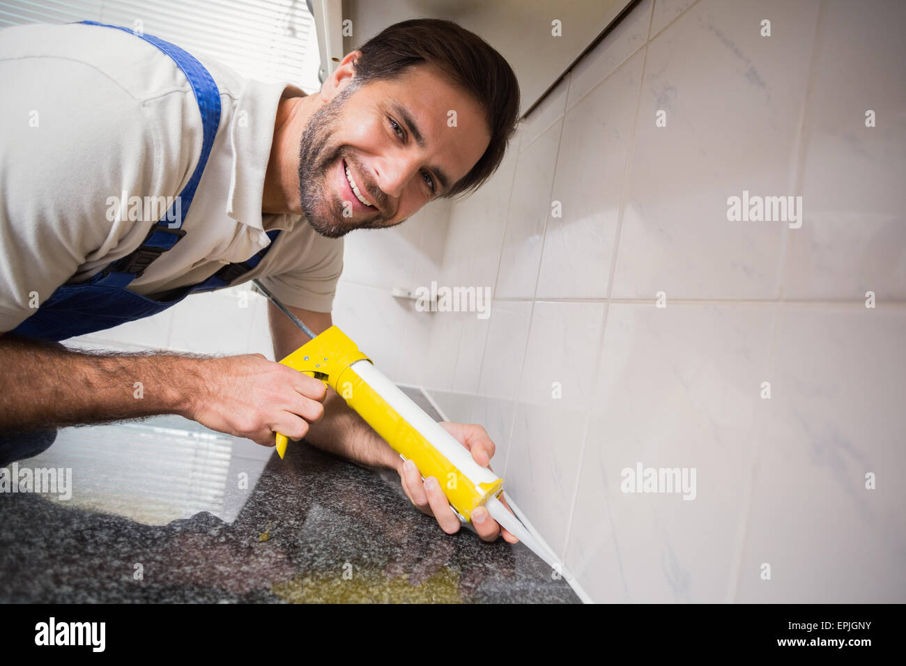 Plumber putting filling in between tiles Stock Photo - Alamy